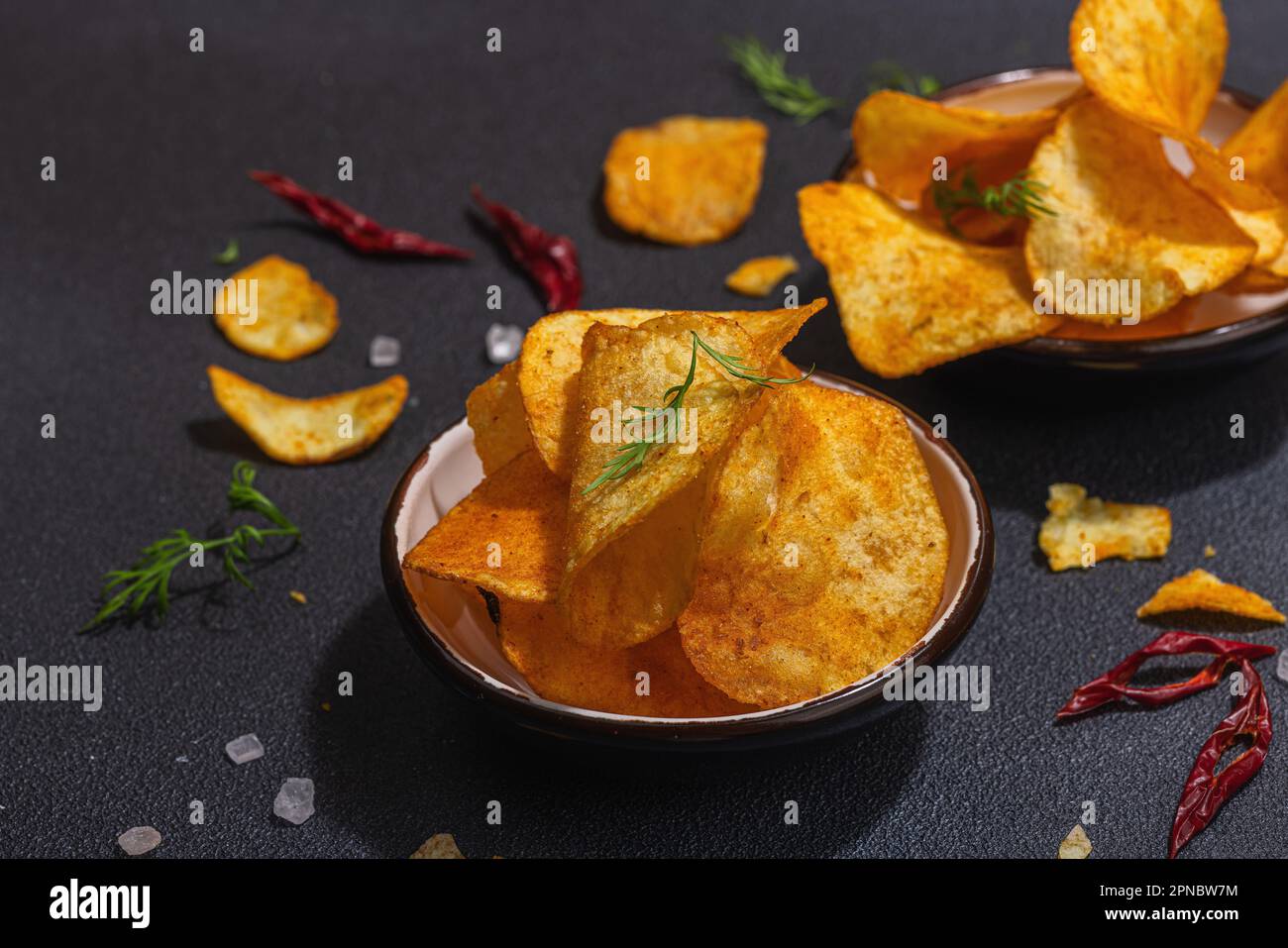 Bowls of homemade potato chips served with chili pepper, parsley, seal ...