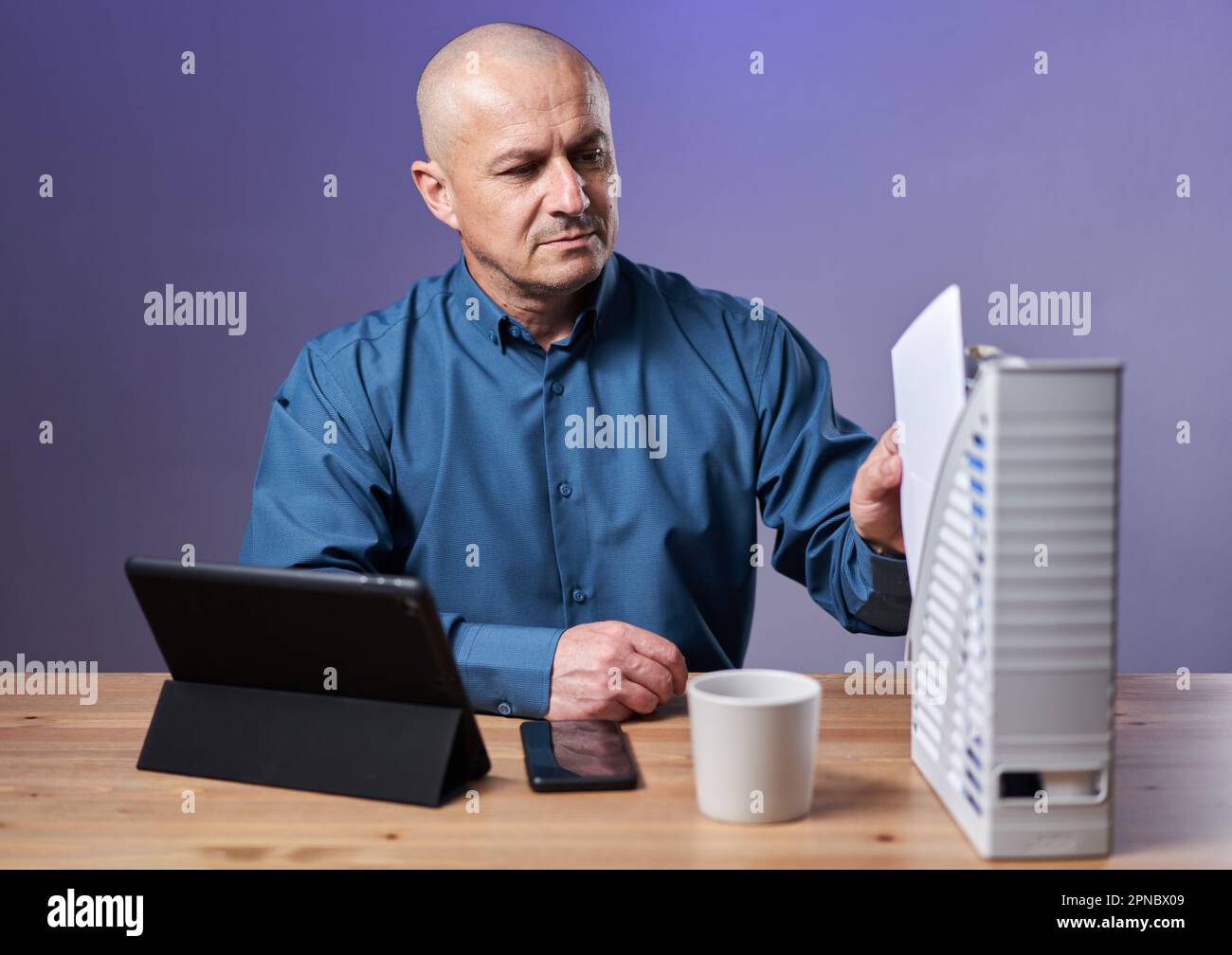Businessman working with files and folders and tablet at his desk, over ...
