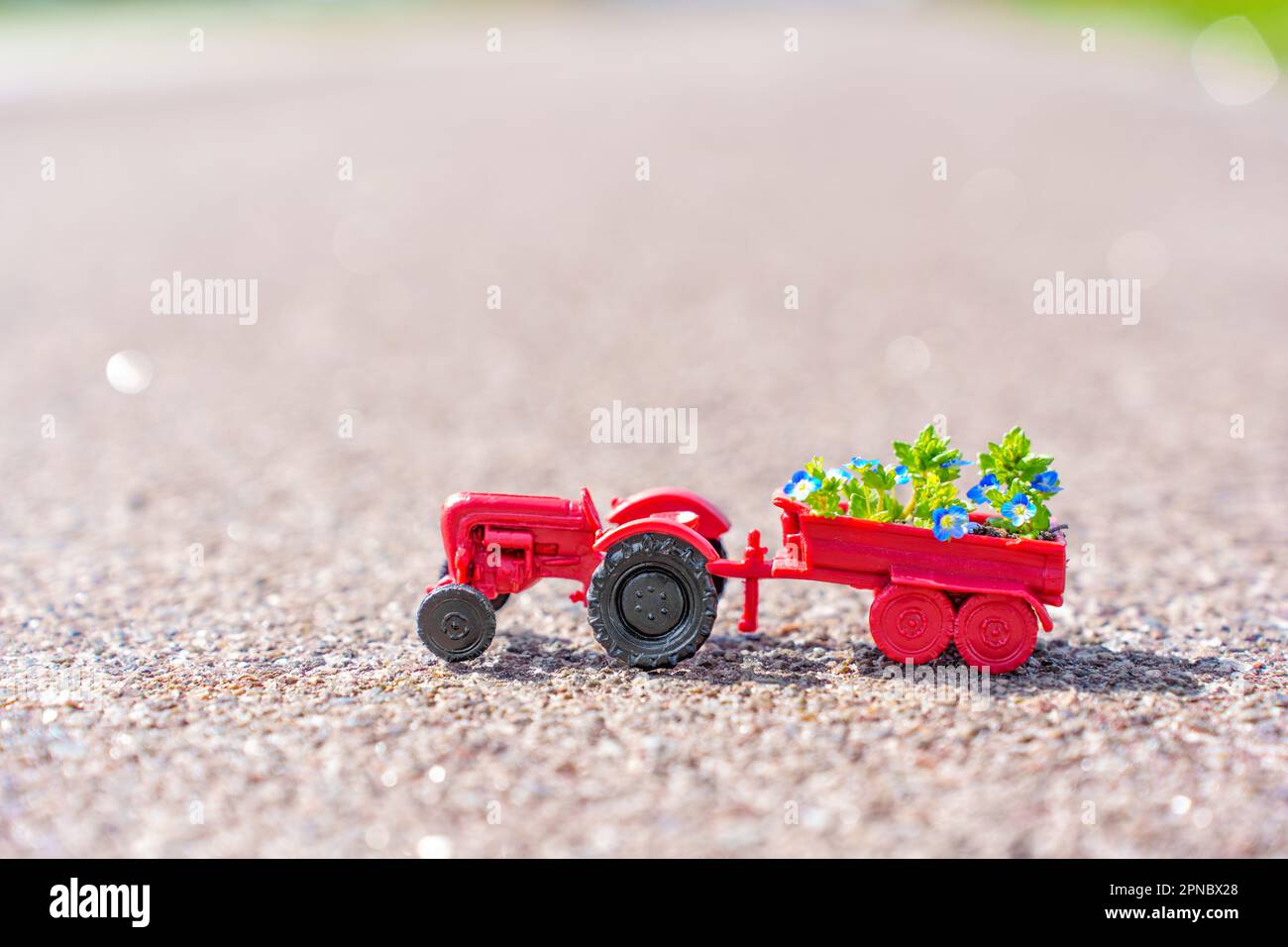 Red toy tractor transporting a flower bed full of colorful spring ...