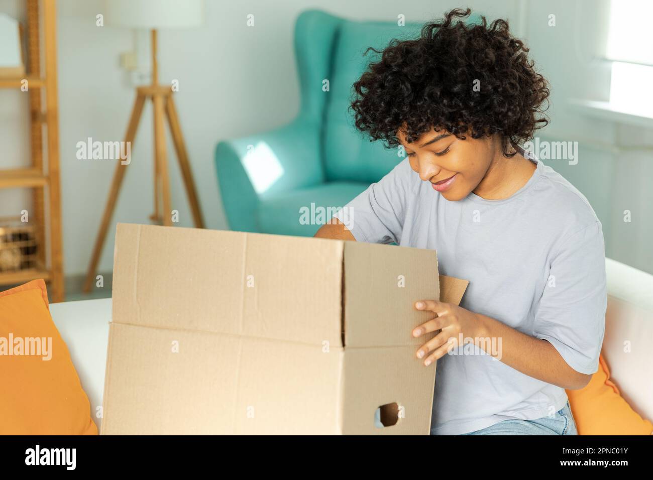 African girl unpacking delivery looking in box. Happy woman opening ...