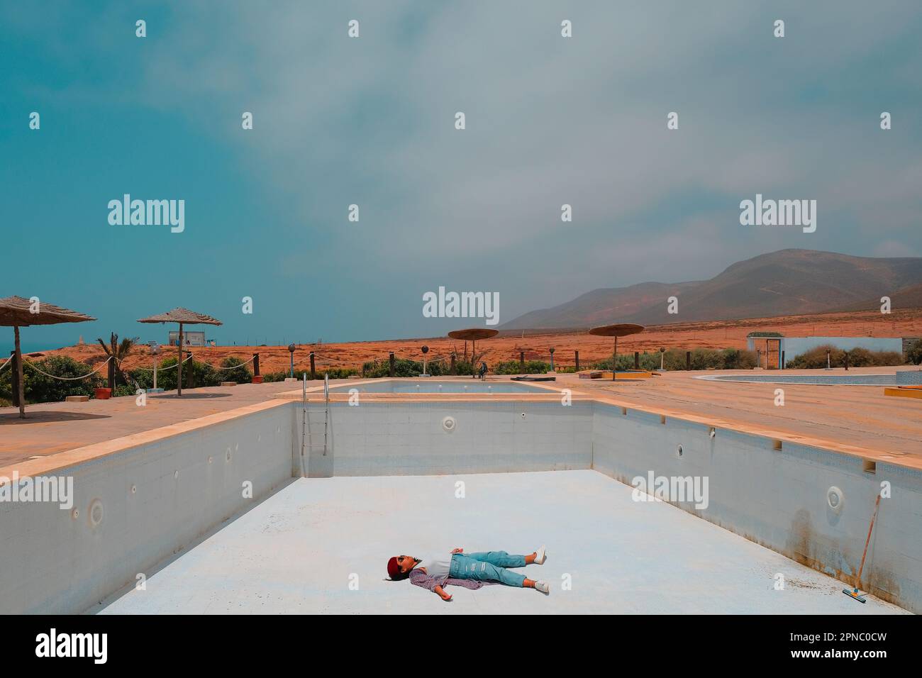 Young female tourist lies down on large empty hotel pool in Morocco ...
