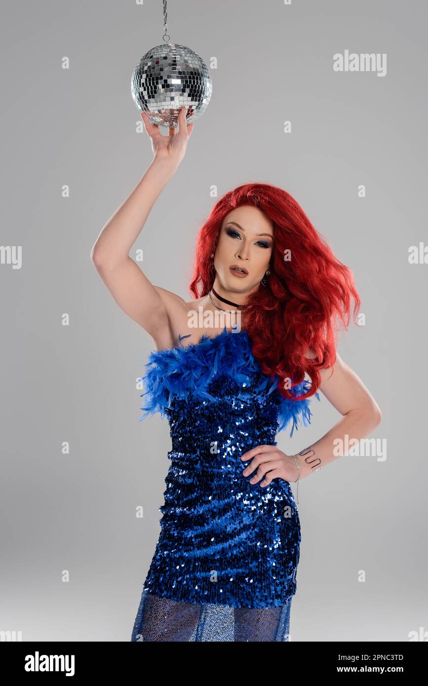 Elegant drag queen in dress touching disco ball and posing isolated on ...