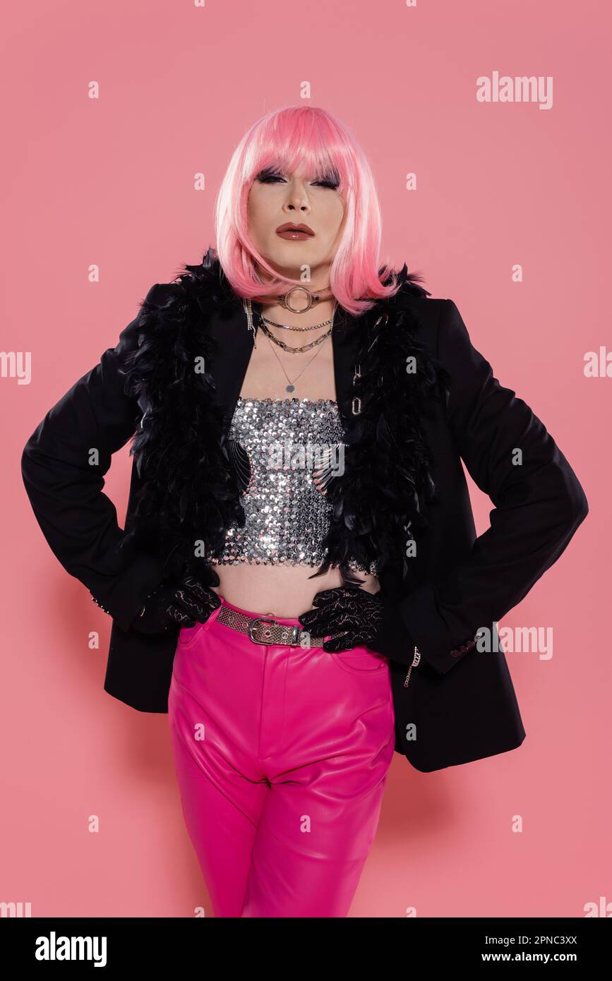 Glamorous drag queen in jacket and sparkling top posing on pink ...