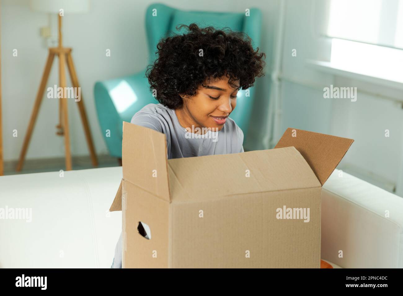 African girl unpacking delivery looking in box. Happy woman opening ...