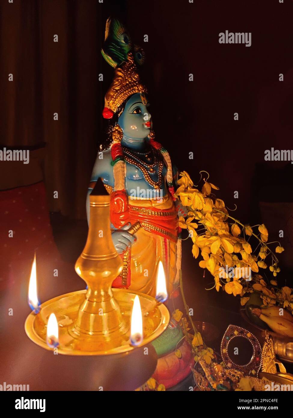 Lit brass oil lamp nilavilakku blue idol of lord krishna cassia fistula ...