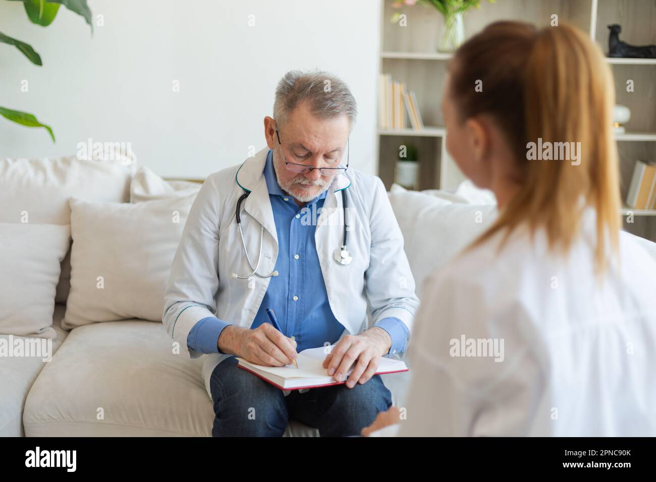 Senior man doctor examining yound woman in doctor office or at home ...