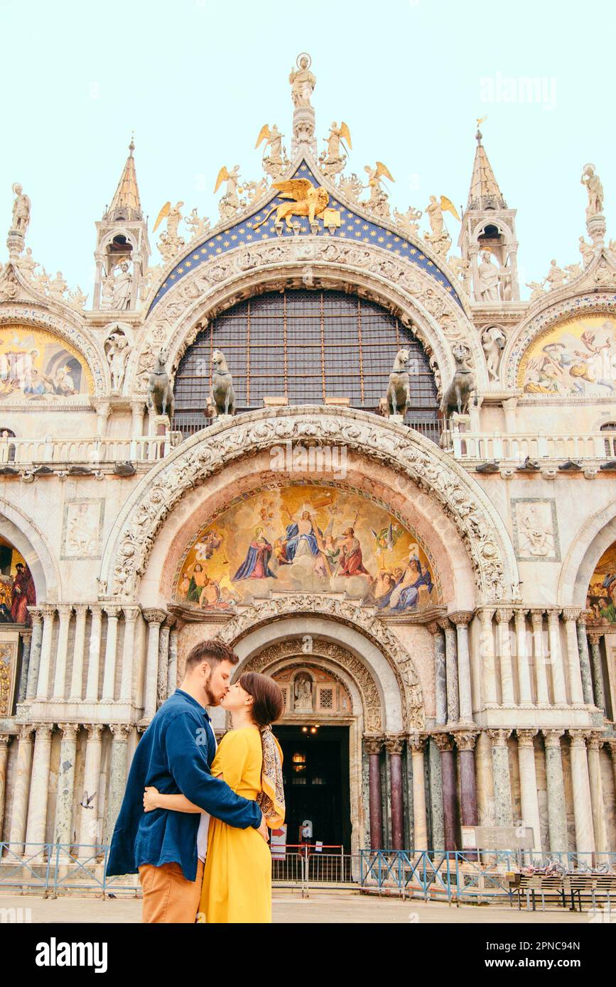 young pretty couple kissing in front of saint marks basilica venice ...