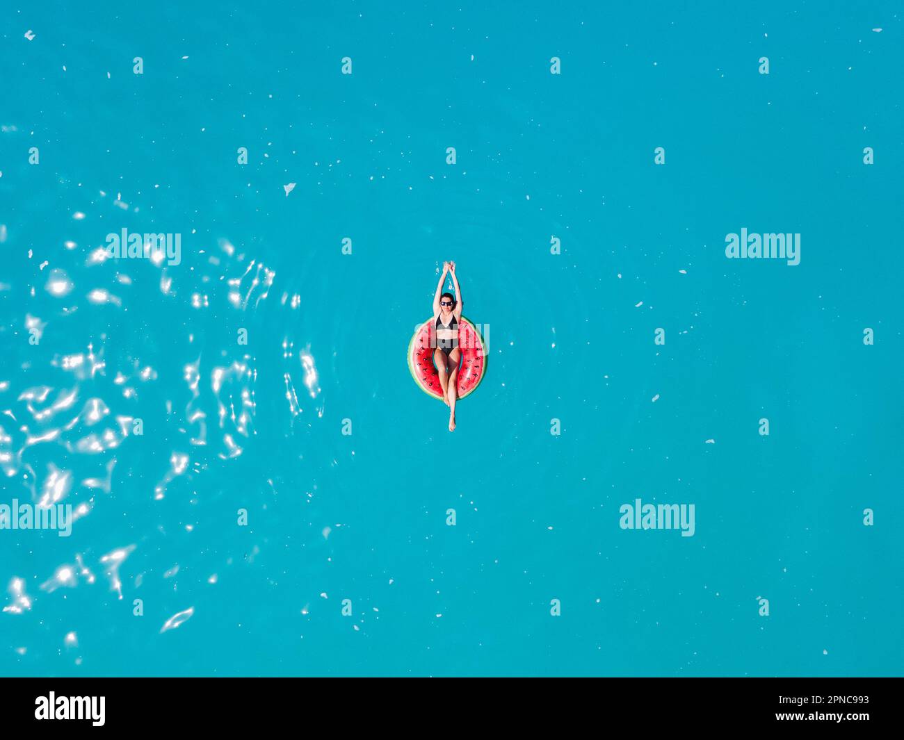 overhead view of woman floating on inflatable ring in blue sea water ...