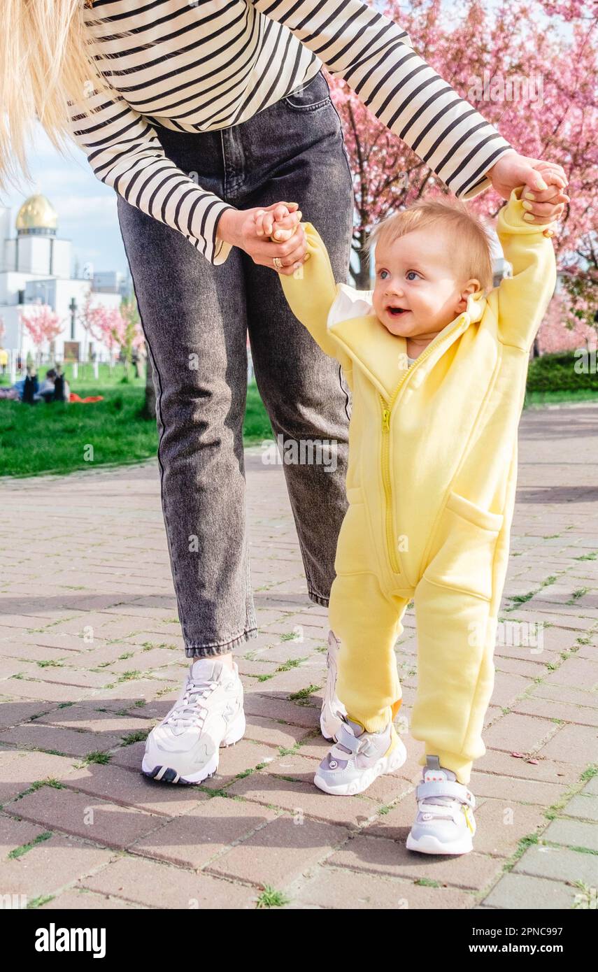 Baby's first steps with loving mother's help Stock Photo - Alamy