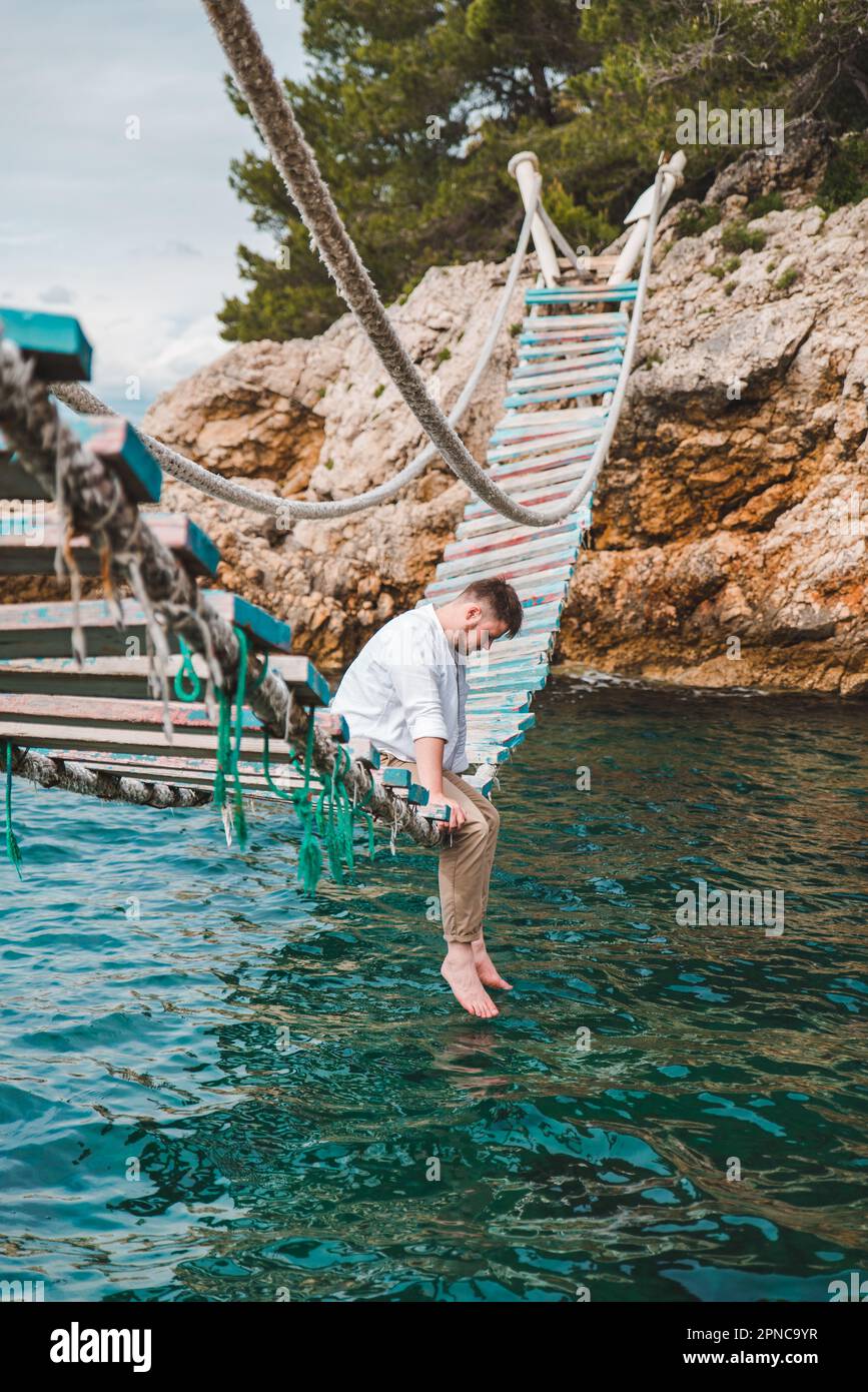 man sitting at suspension bridge enjoying sea view and nature calmness ...