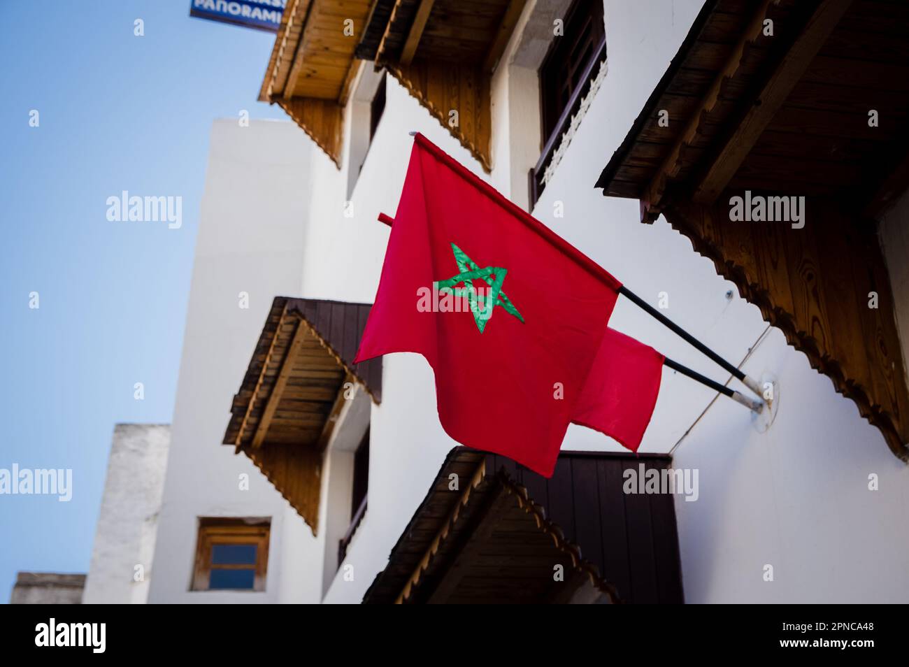Red flag of Morocco waving in the wind against blue sky background ...