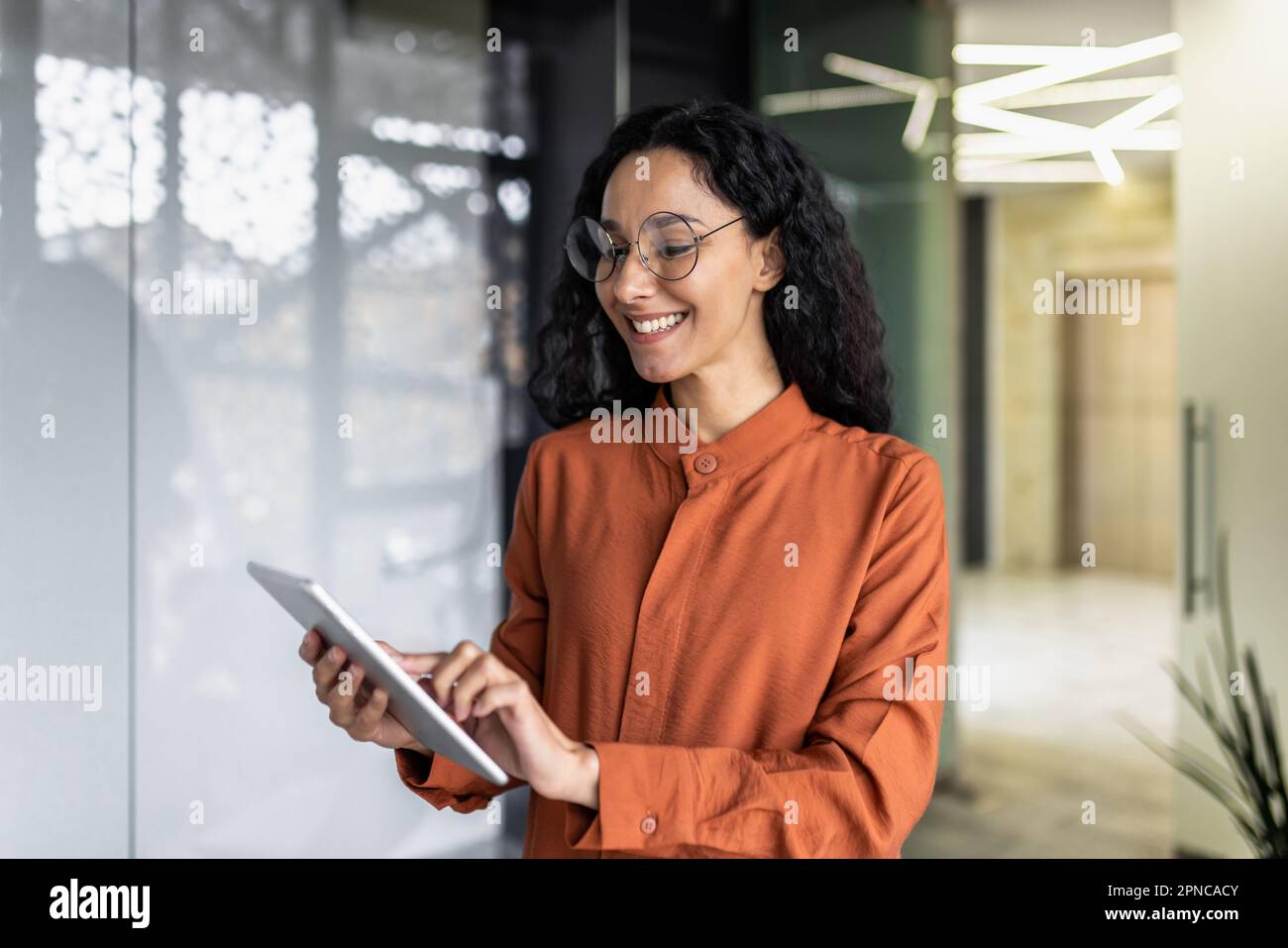 Indian female programmer standing inside the office with a tablet computer in her hands, the ...