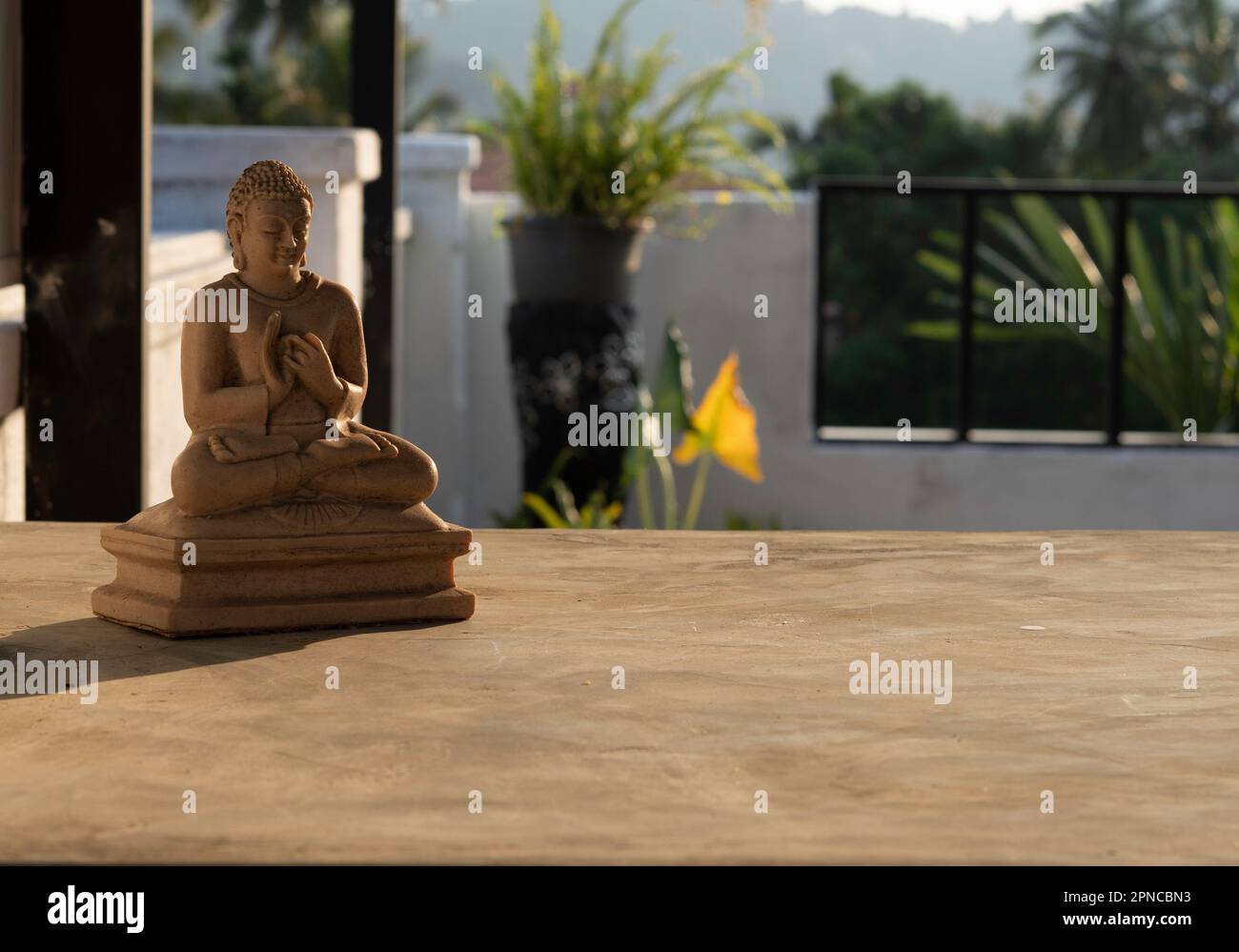 Buddha statue meditating on a concrete table with a white wall and ...