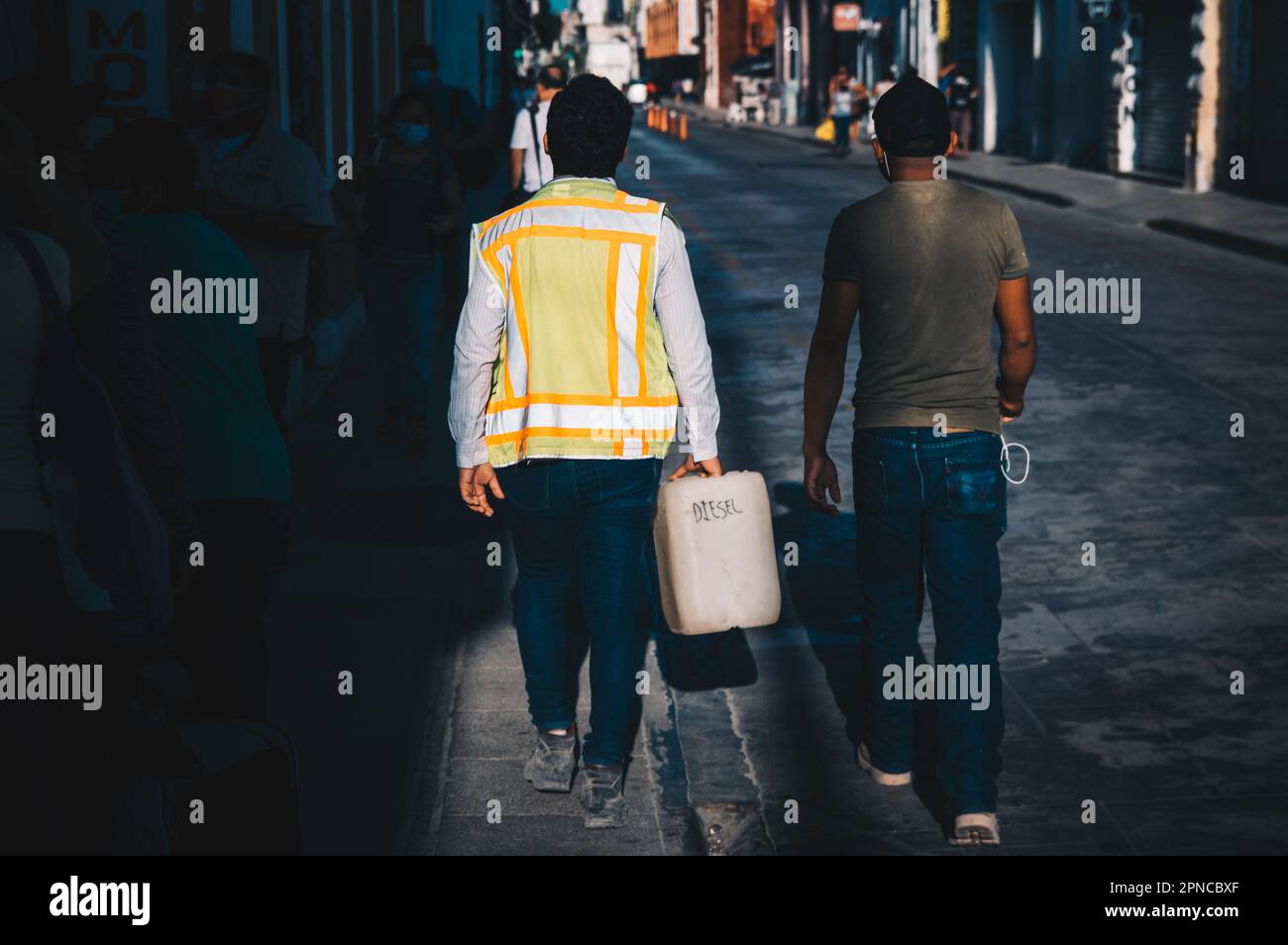 Two sad men walking with empty can of diesel fuel in the street in the ...