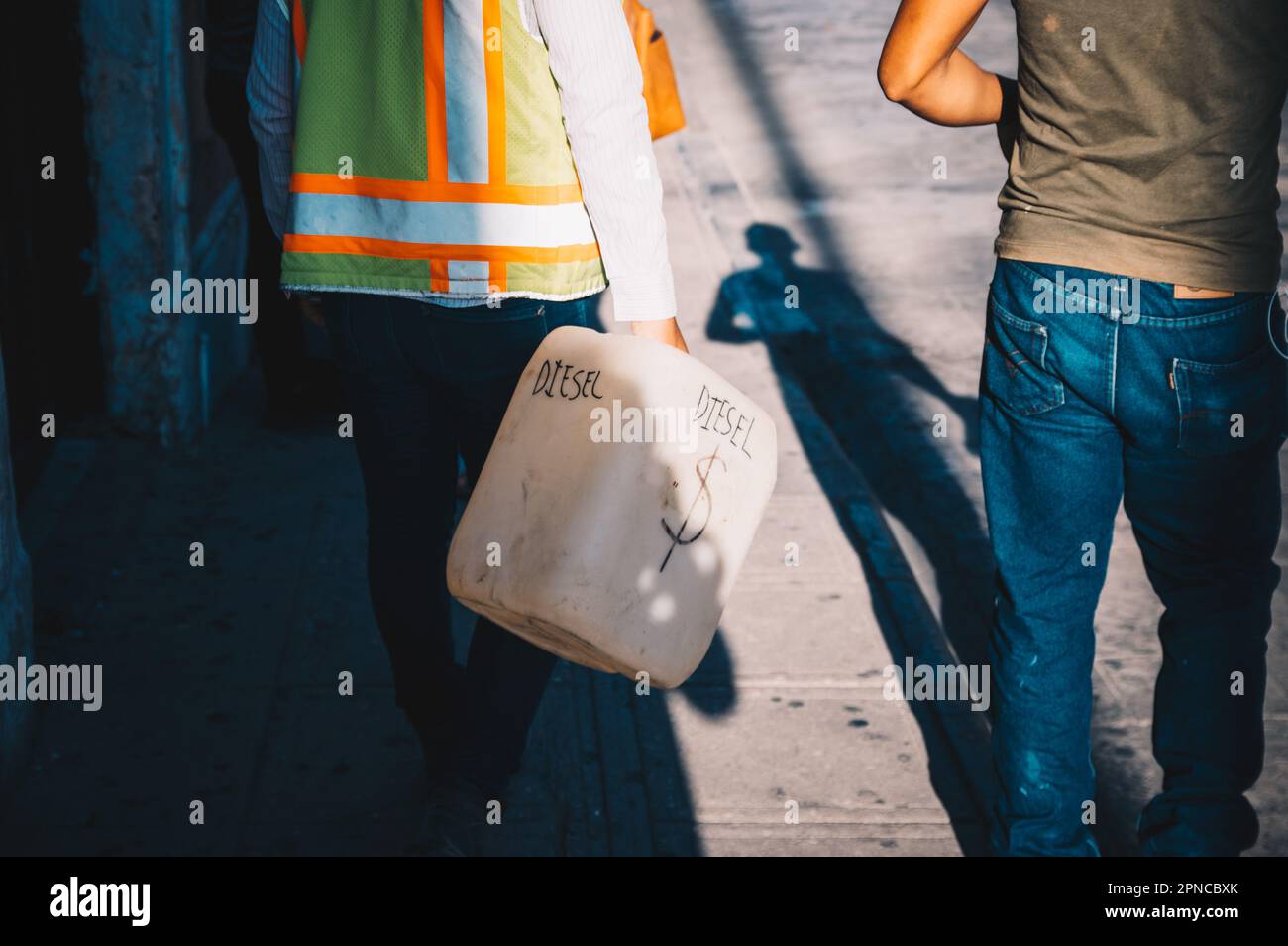 Two sad men walking with empty can of diesel fuel in the street in the ...