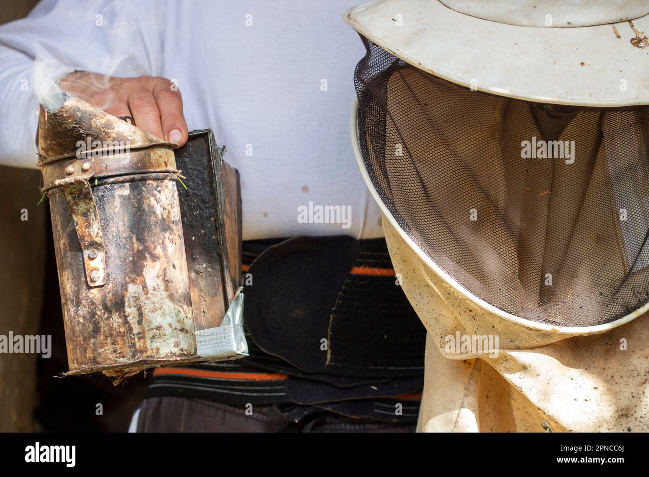 Beekeeping smoker. The beekeeper lighting it with different fuels and ...