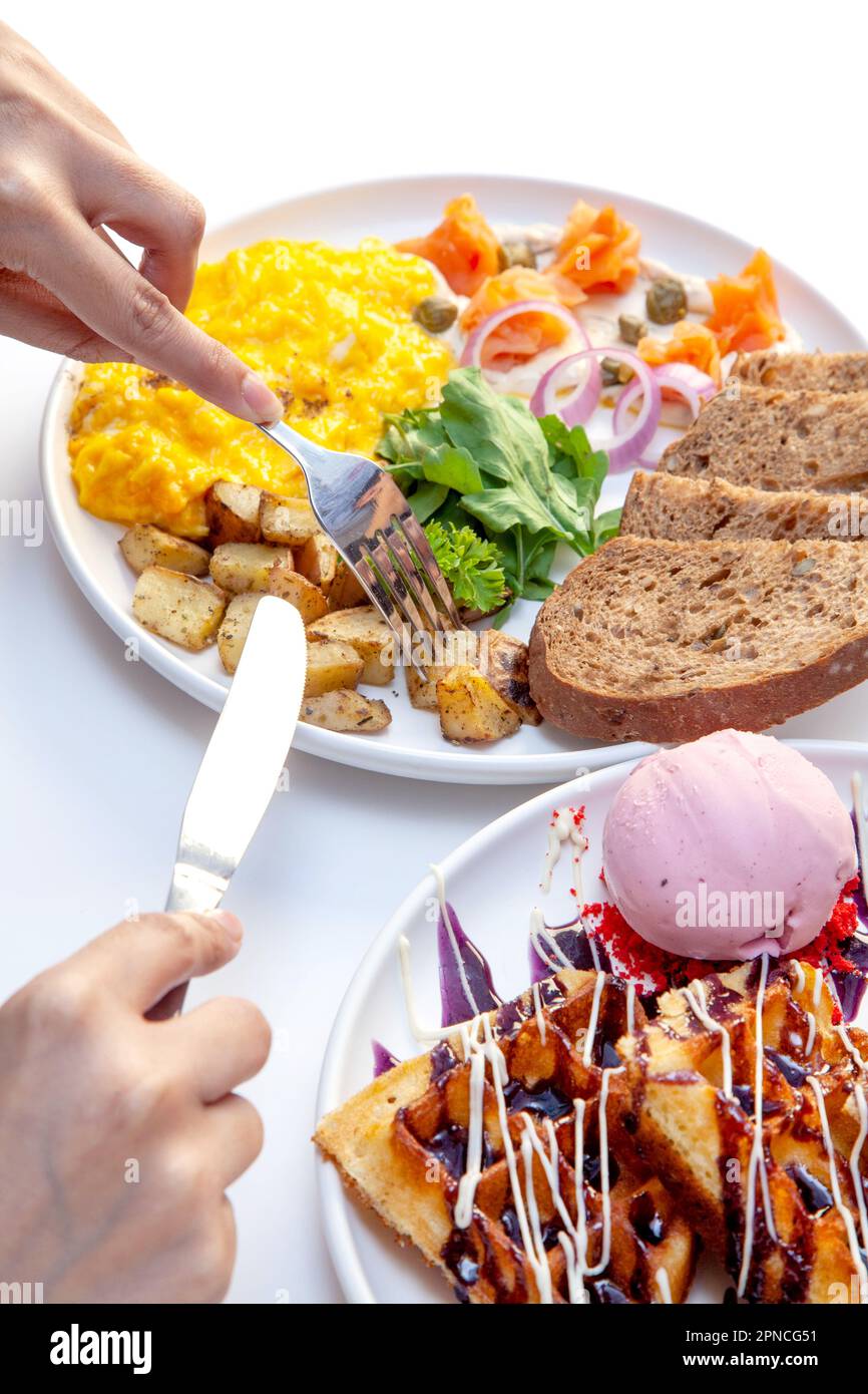 Eating with fork and knife smoked salmon with dill cream capers and ...