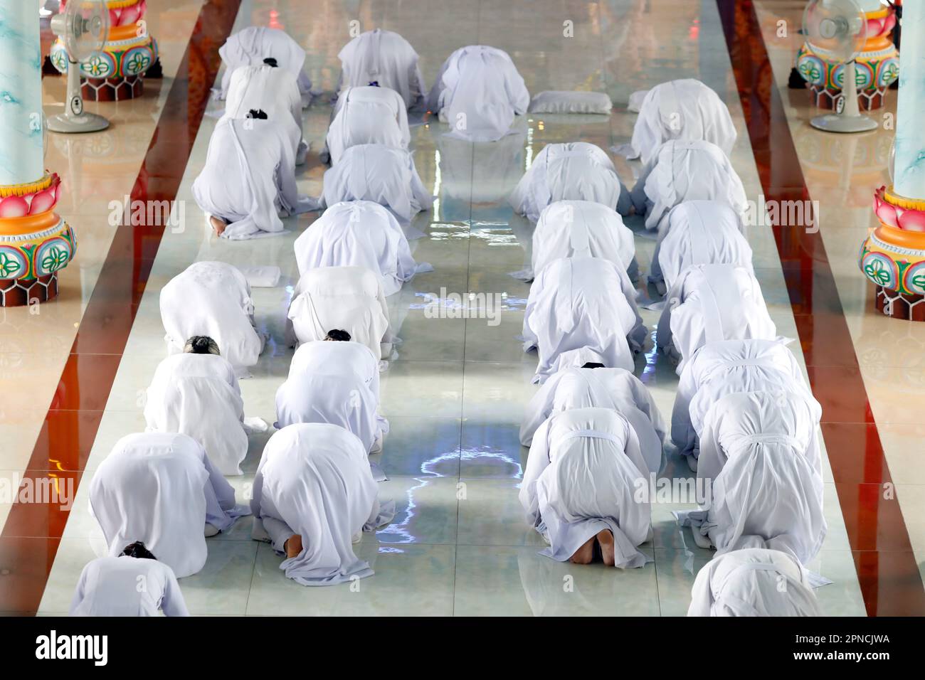 Cao Dai temple. Caodaist disciples sitting during ceremony, Tan Chau ...