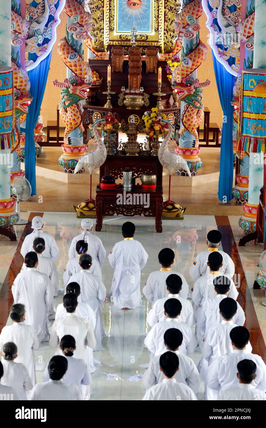 Cao Dai temple. Caodaist disciples sitting during ceremony, Tan Chau ...