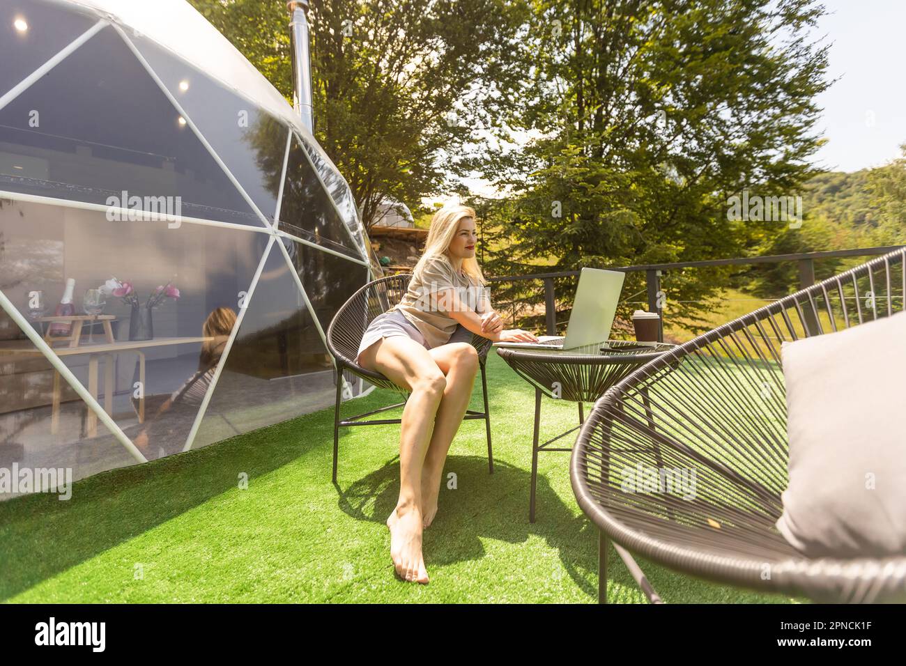 Woman working on laptop geo dome tents. Green, blue background. Cozy, camping, glamping, holiday ...