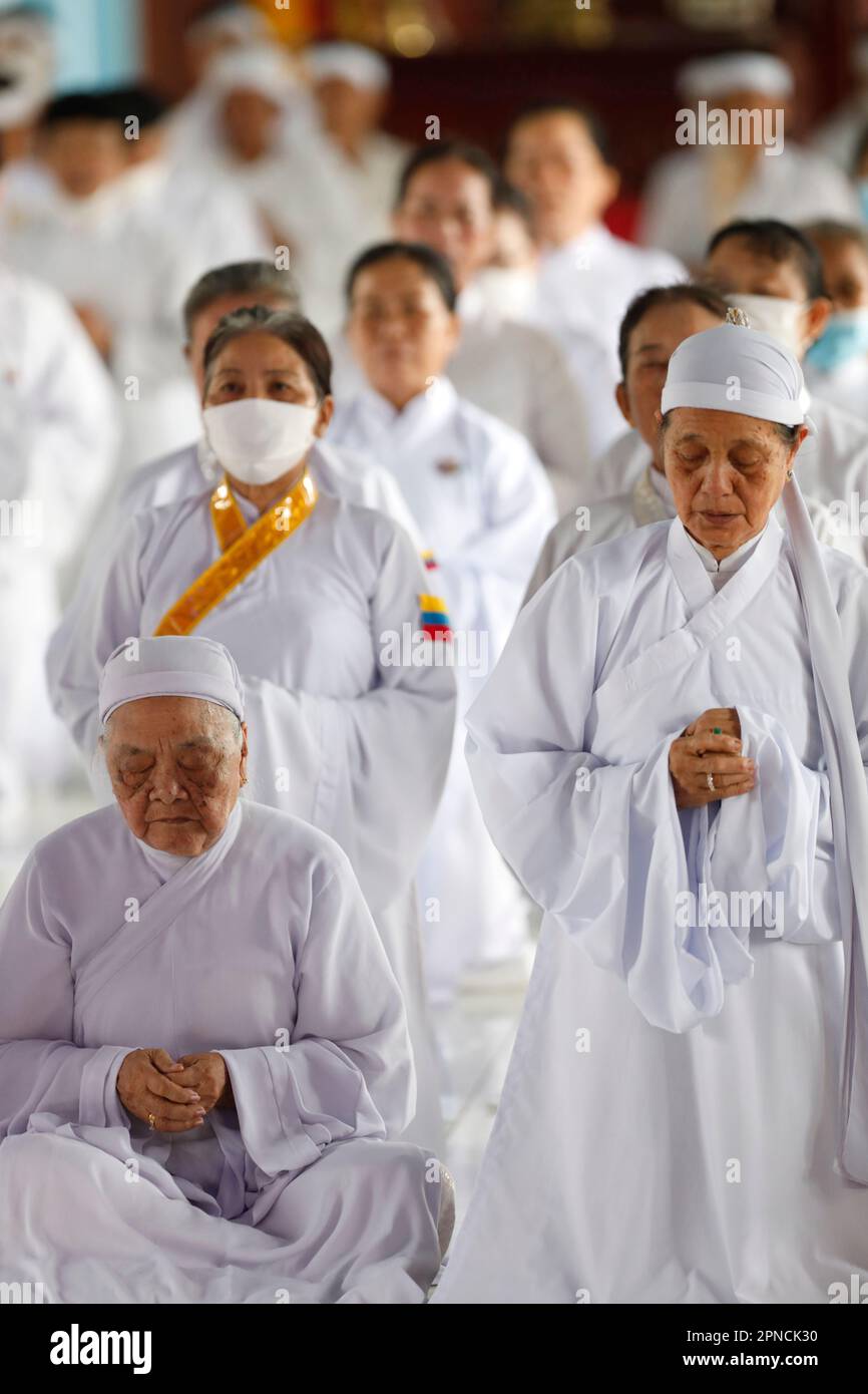 Cao Dai temple. Caodaist worshippers at ceremony. Meditating followers ...