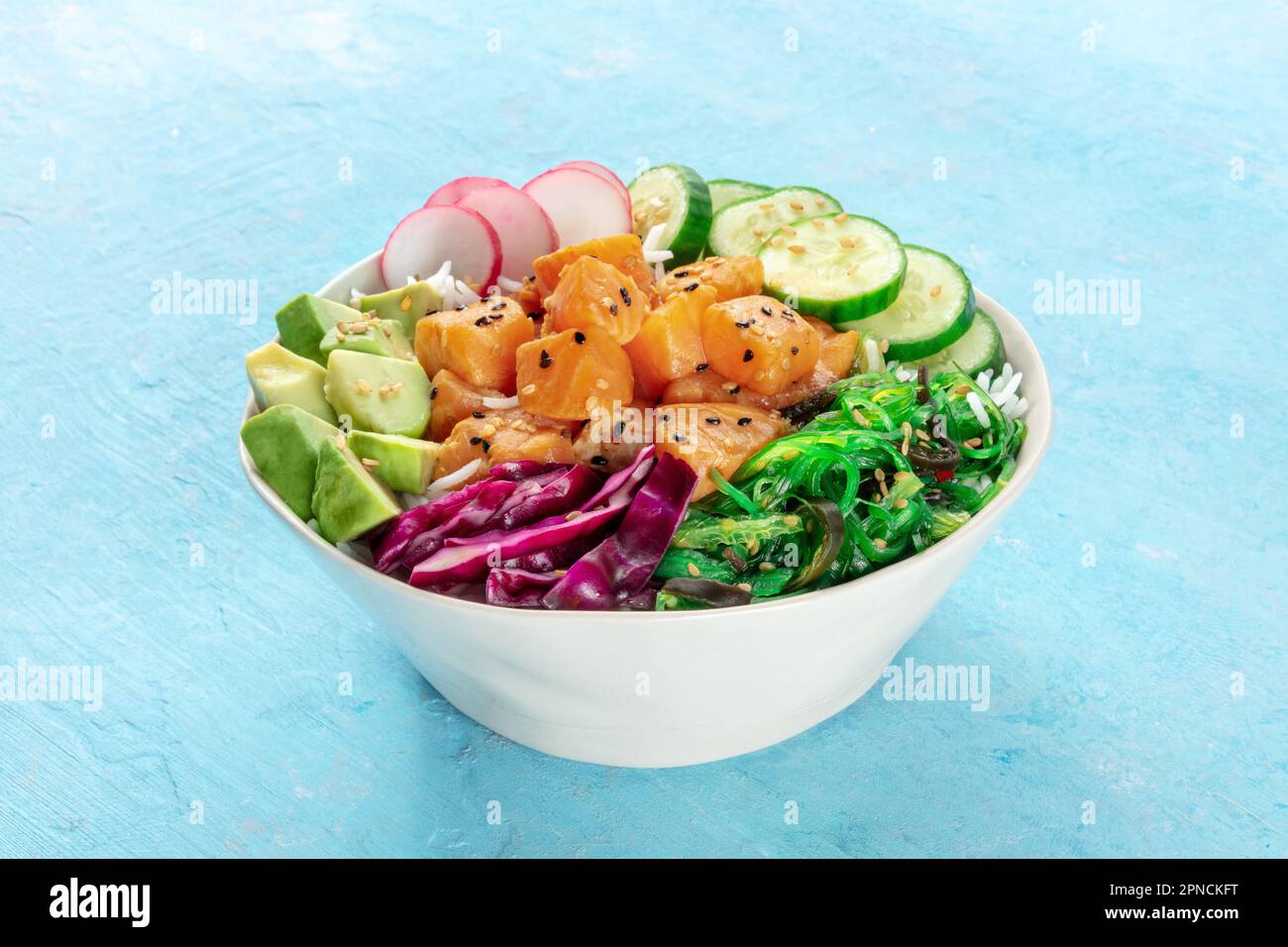 Salmon poke bowl with avocado, cucumbers, wakame, radish, and purple ...
