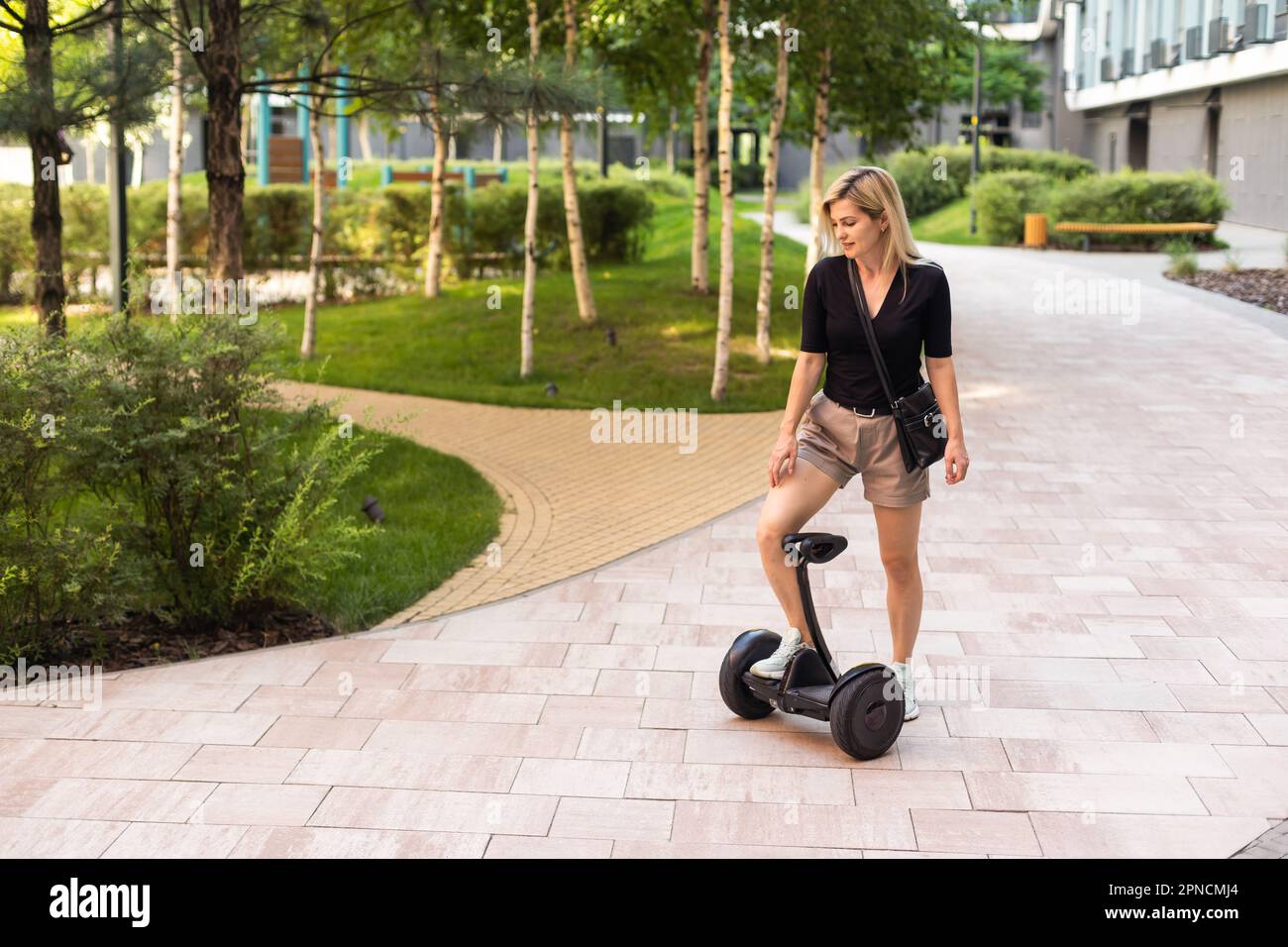woman riding electric mini segway hover board scooter in green park ...