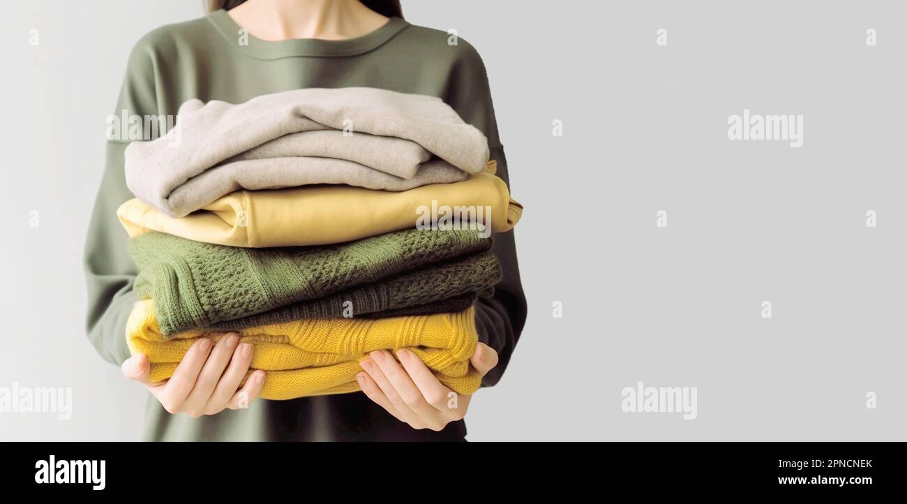 Woman's hand holding a stack of clothes. Clothes Donation, Renewable ...