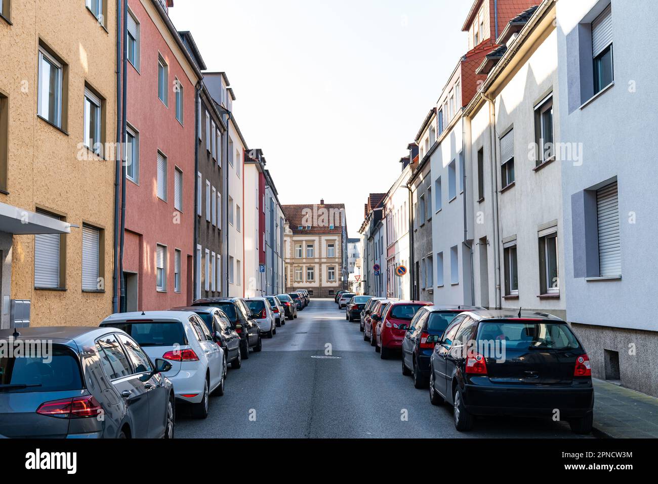 Narrow city lane with cars parked tightly on both sides. Faded ...