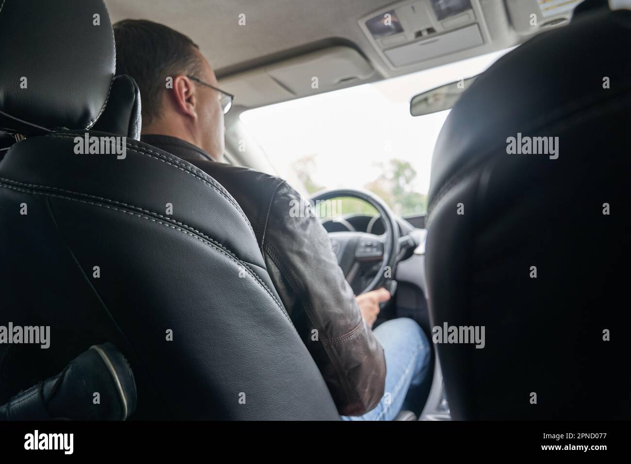 A man with glasses and a leather jacket looks at the road. Small baby ...