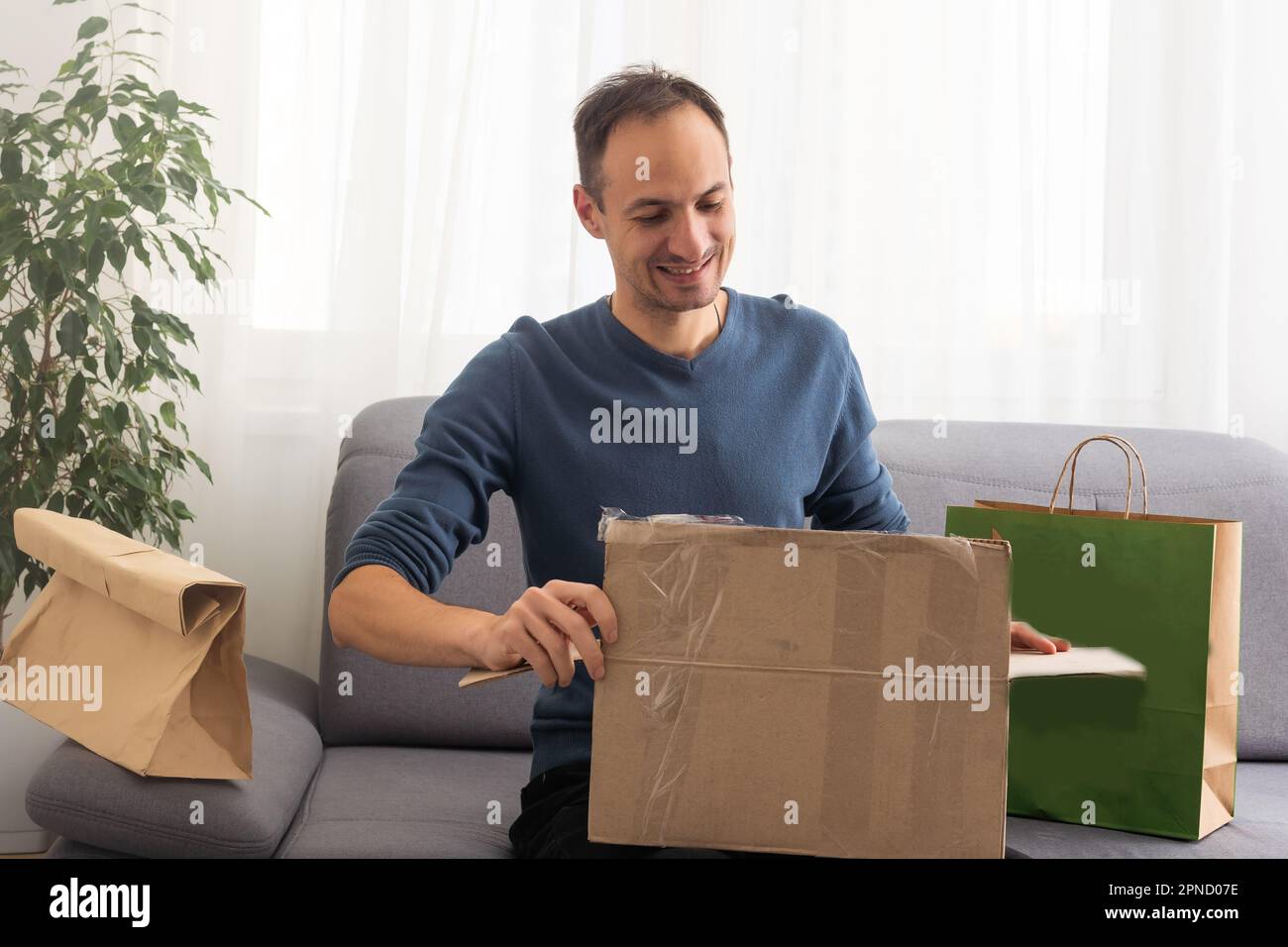 Present from distant friend. Happy millennial man unpack open box with ...