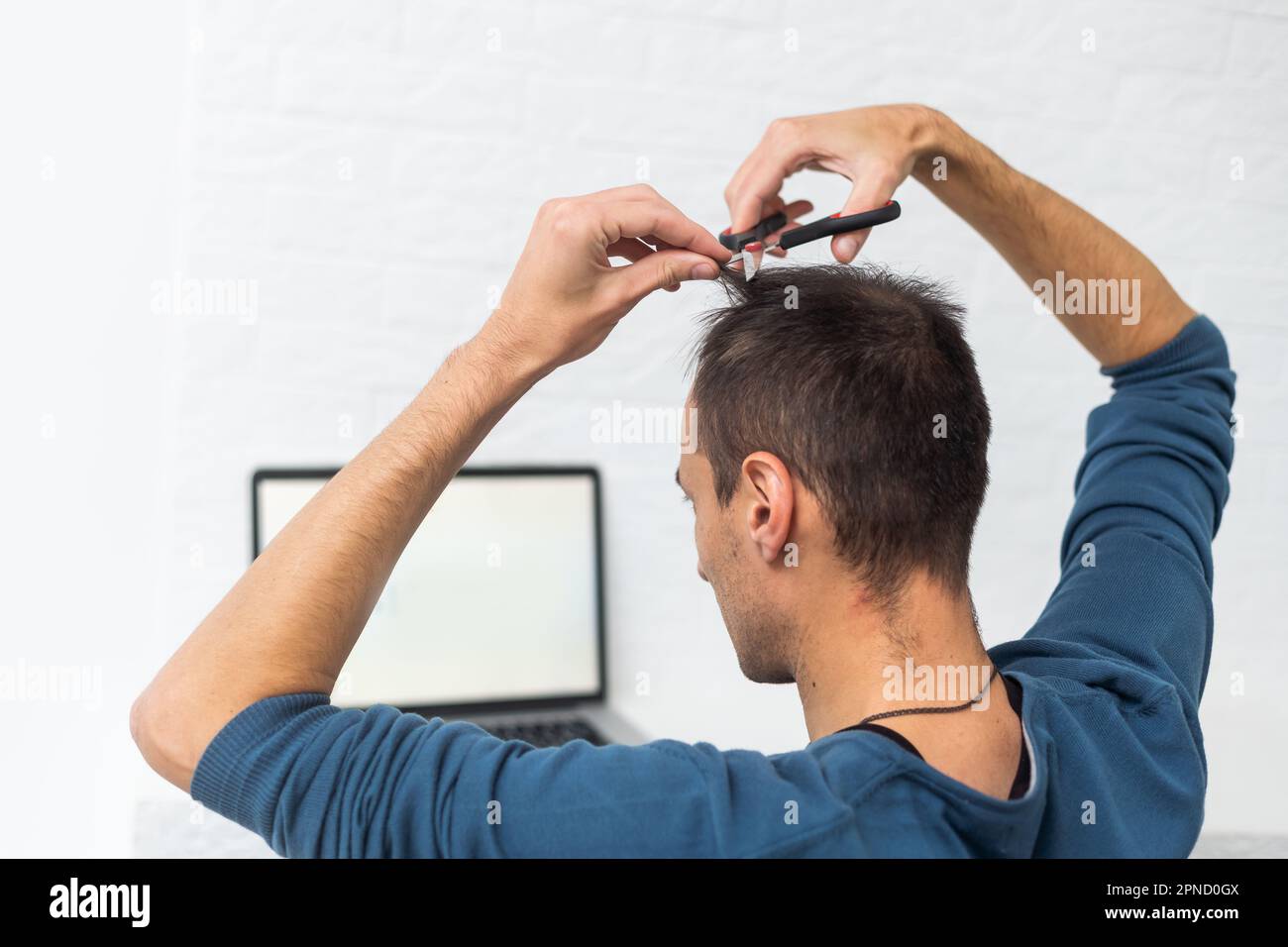 Shaggy man is trying to cut his own hair with the help of scissors and ...