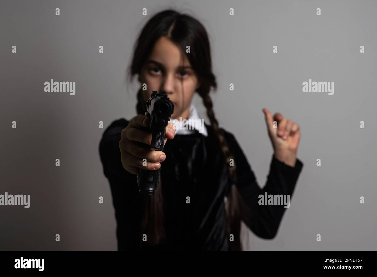 Wednesday Addams. Gothic girl with pistol, weapon Stock Photo - Alamy