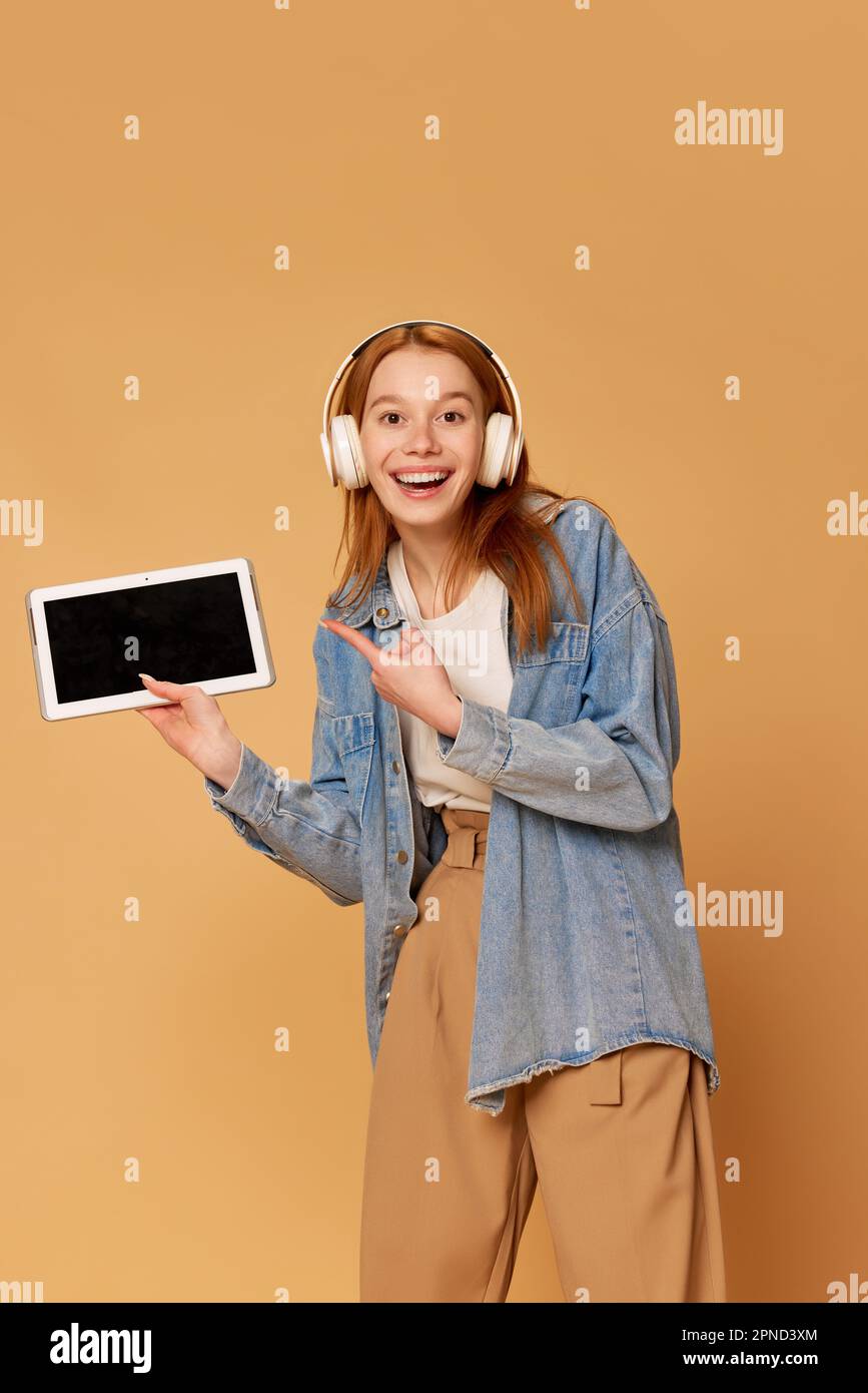 Portrait with student, girl wearing headphones holding tablet and ...