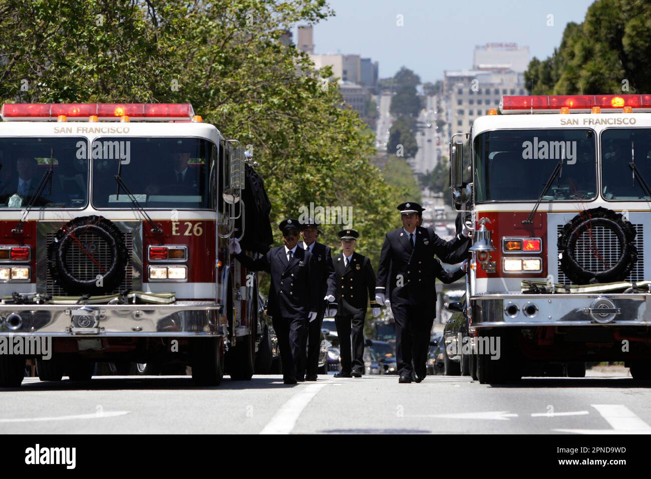 Firefighters walk alongside the two fire engines carrying the caskets ...
