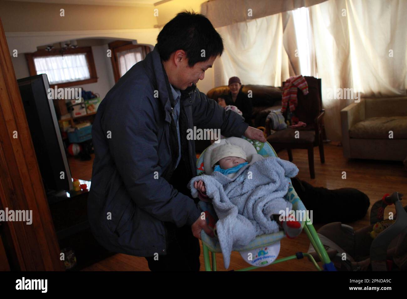 Mark Gin (left) carries his daughter Emily Gin, 8 months (second from ...
