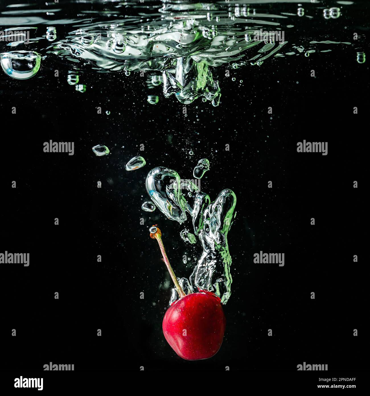 ripe cherries fall into the water raising splashes and air bubbles ...
