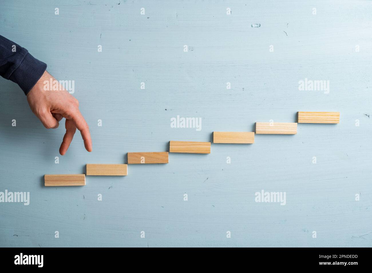 Male hand walking his fingers up the stairs made of wooden pegs ...