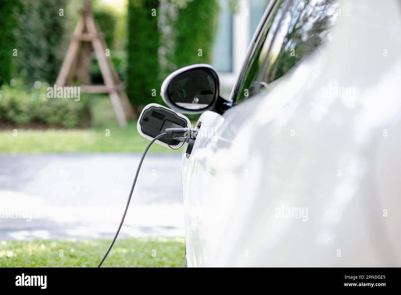 Closeup electric vehicle plugged-in with cable from charging point ...