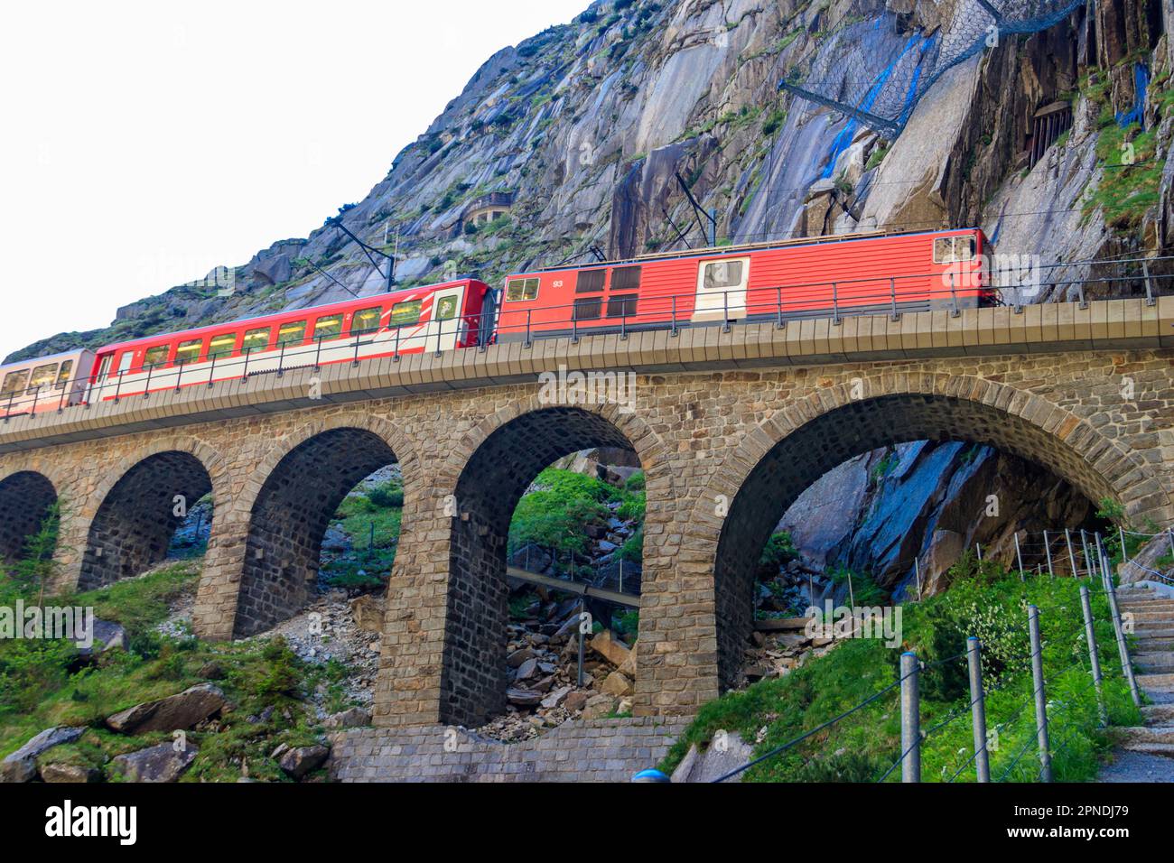 Red train passing by Devil's bridge at St. Gotthard pass on the Swiss ...