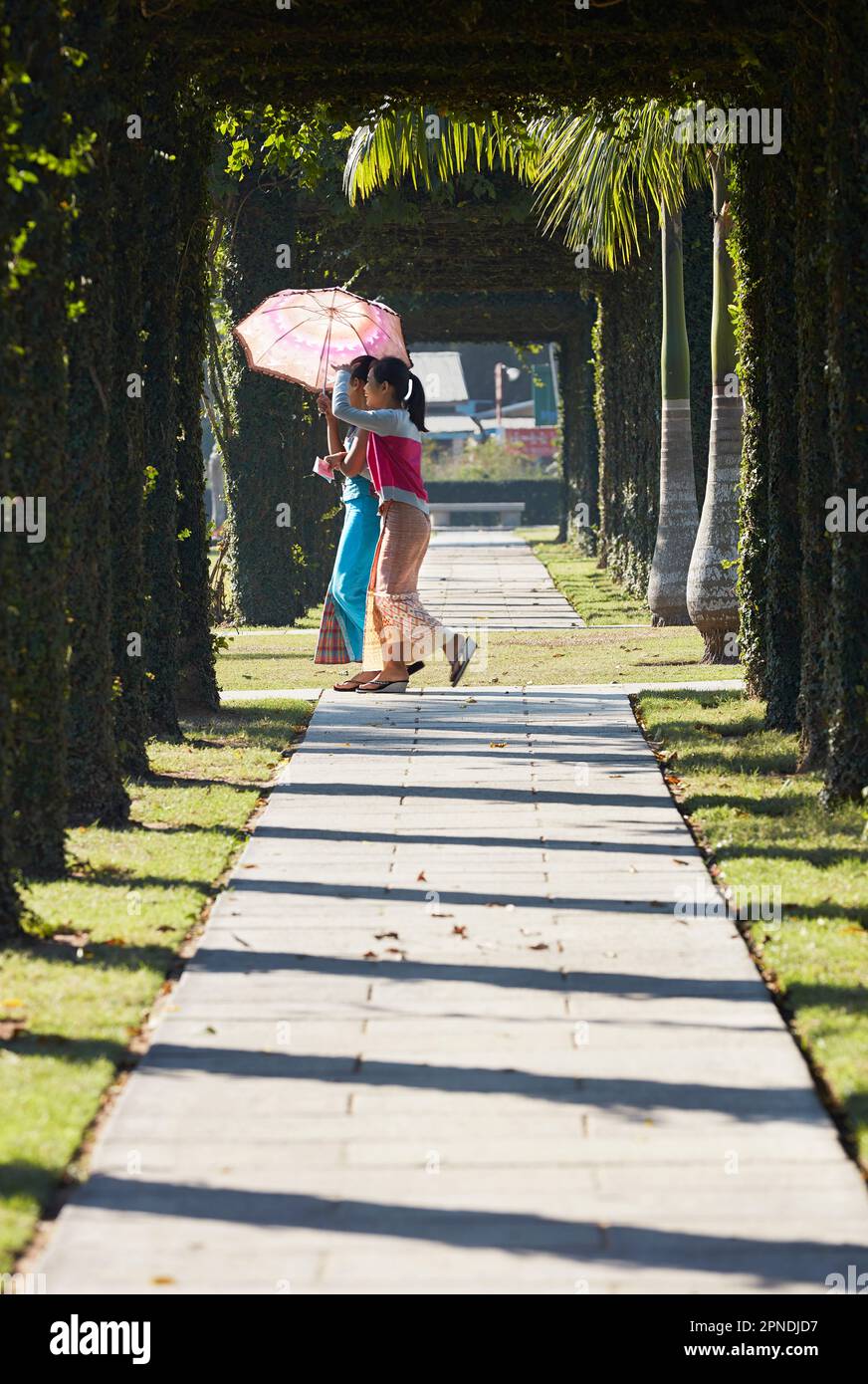 Two girls with an umbrella walk inside the Rangoon Memorial, located in ...