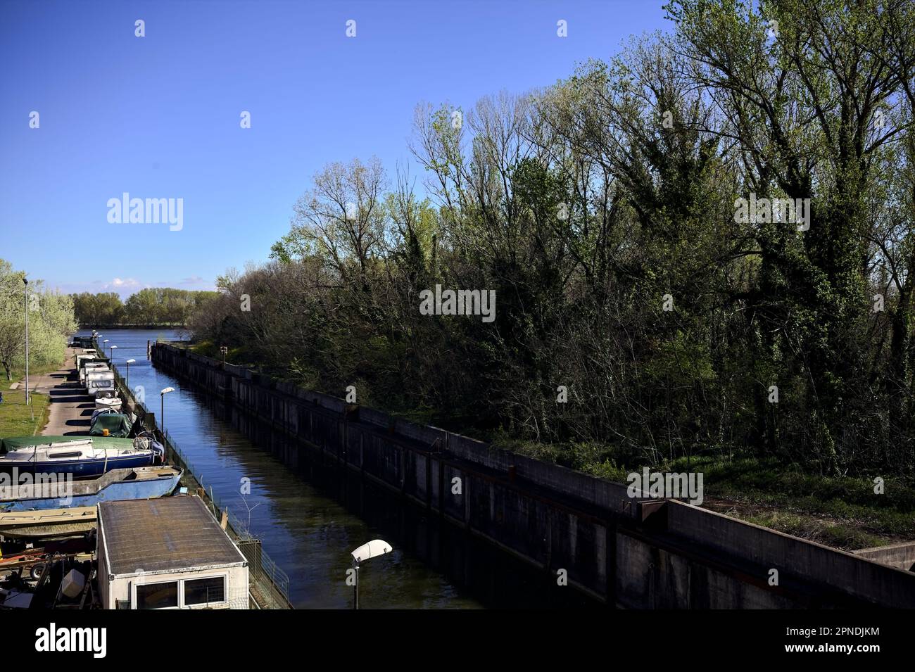 Concrete channel next to a forest with parked cars and street light on ...