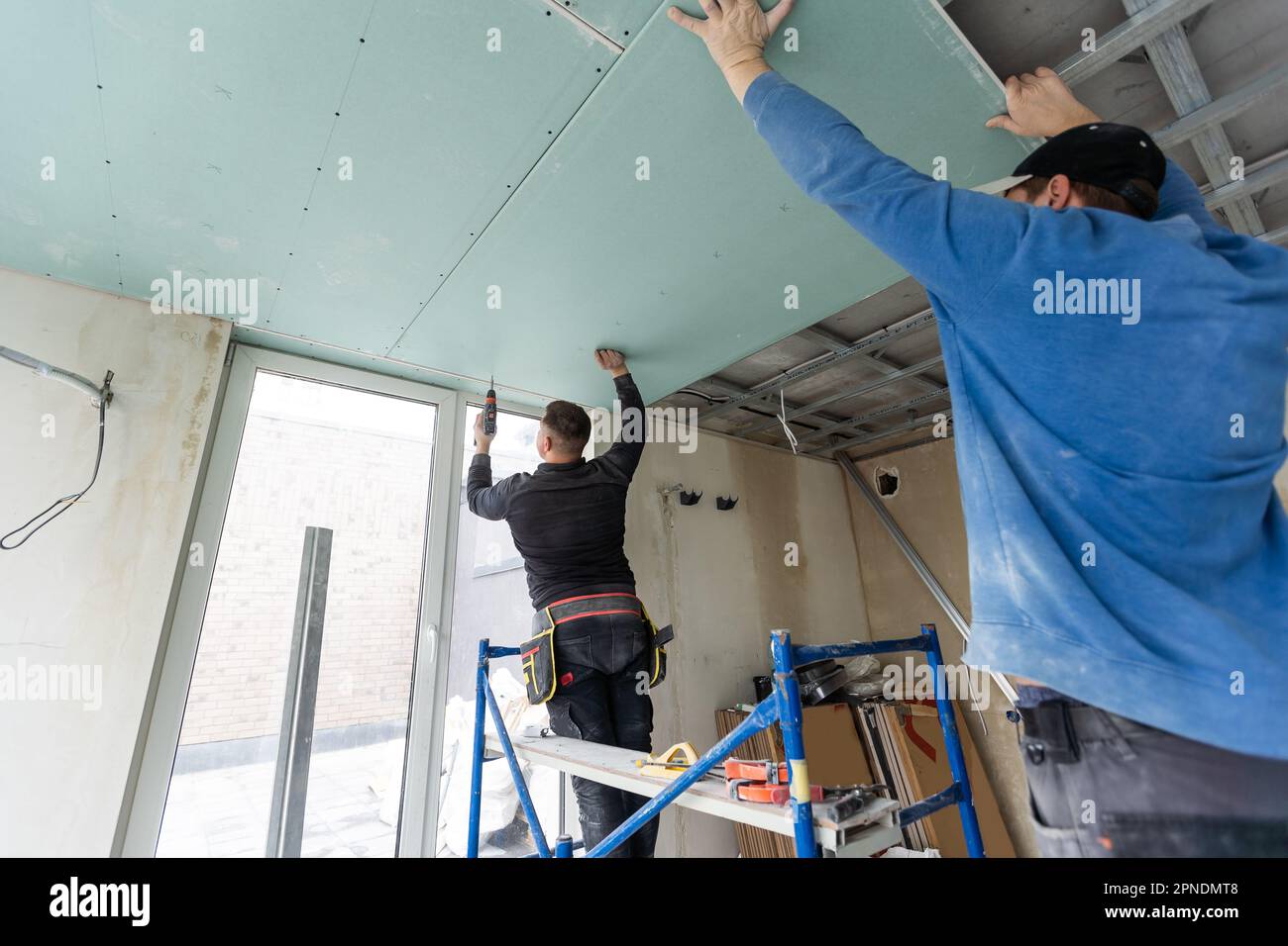 Construction worker installation ceiling work Stock Photo - Alamy