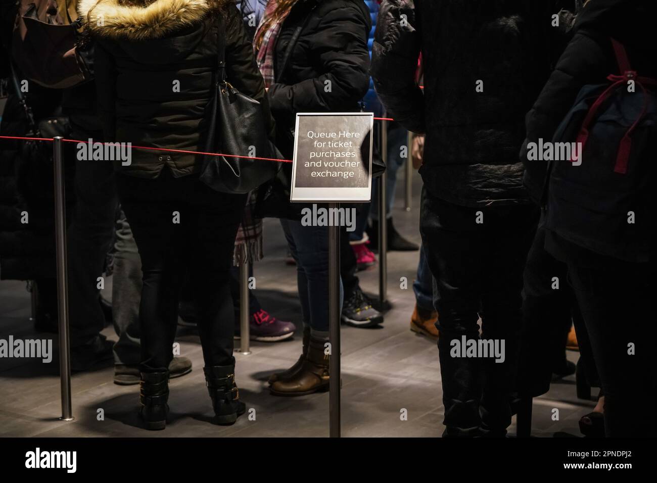 Group of people wearing winter clothes waiting indoor in line for ...