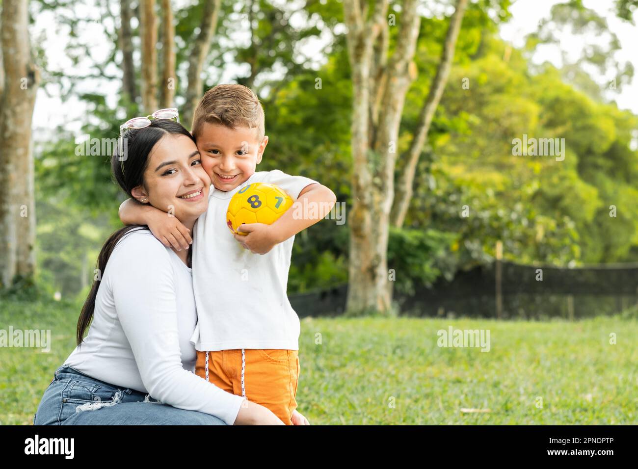 young mother with her son, playing with a ball in the park, girl ...