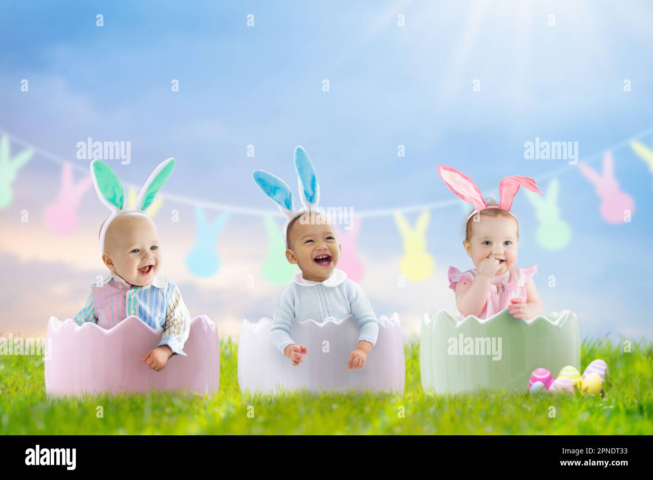 Child on Easter egg hunt. Asian and Caucasian baby with bunny ears in ...