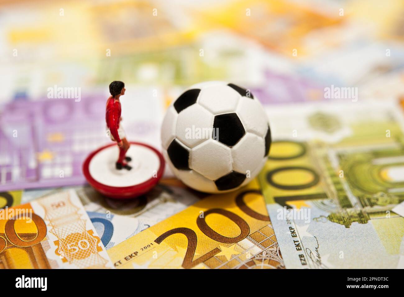 soccer ball and football player figurine over a background of money ...