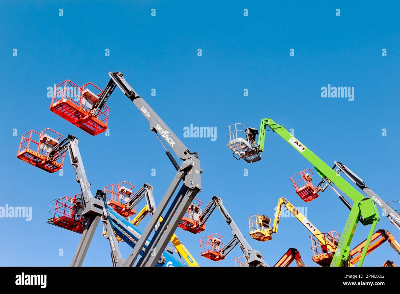 Boom lifts with hydraulic arms extended against a blue sky, pure clear ...