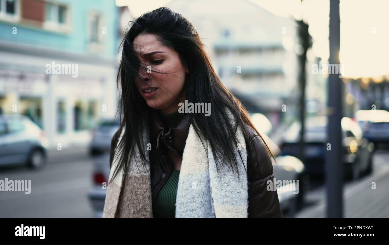 Worried young woman walks in street shaking head in disbelief ...