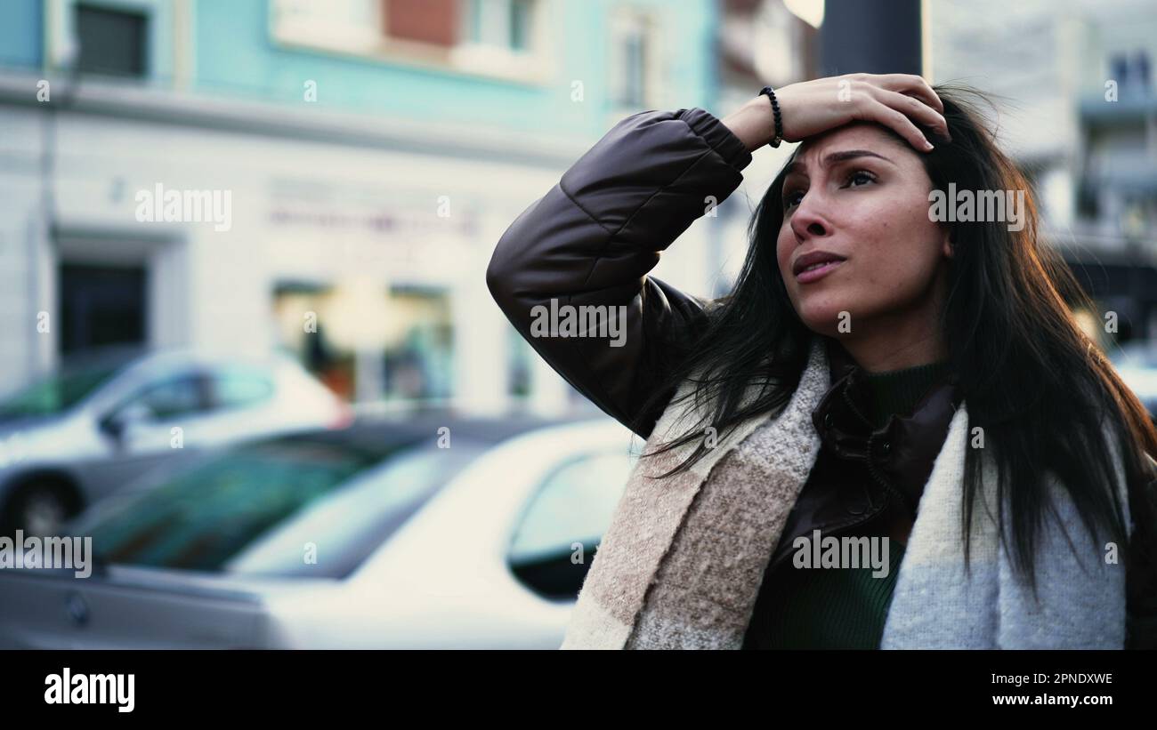 Worried young woman walks in street shaking head in disbelief ...